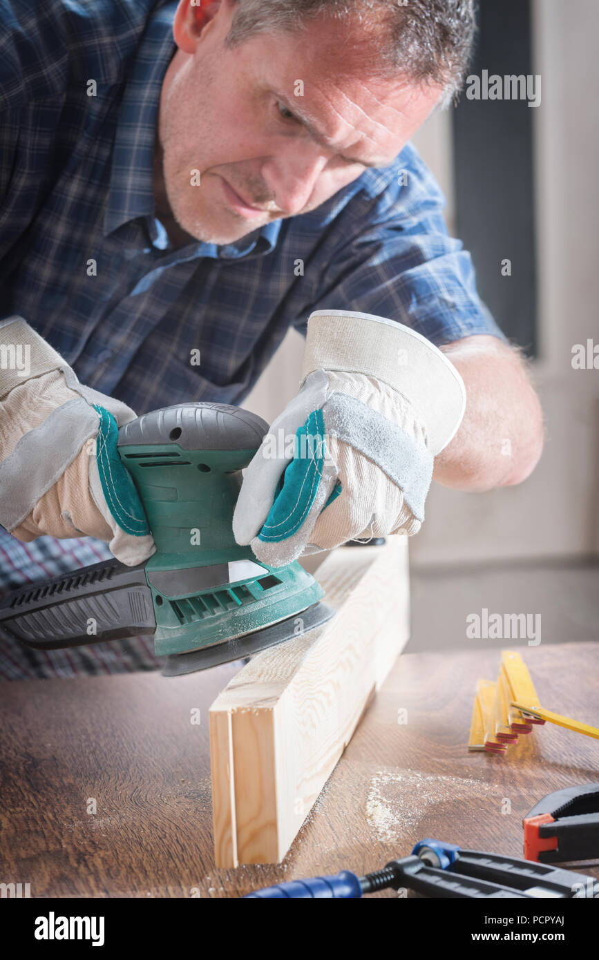 Man sanding a wood with orbital sander in a workshop Stock Photo - Alamy