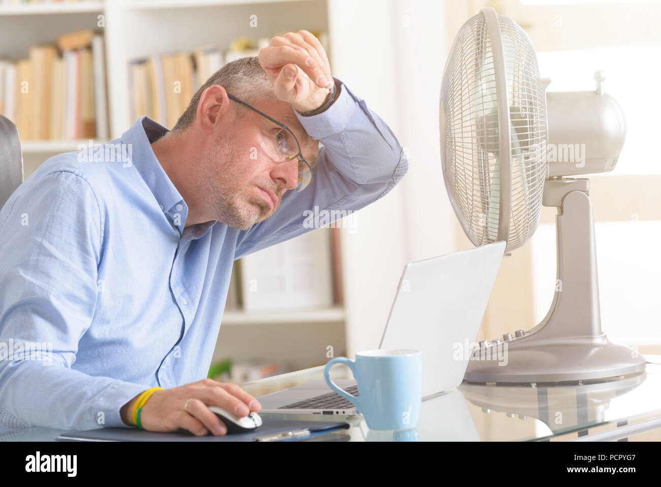 Man suffers from heat while working in the office and tries to cool off ...