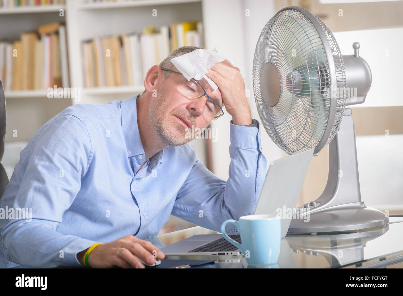 Man suffers from heat while working in the office and tries to cool off ...