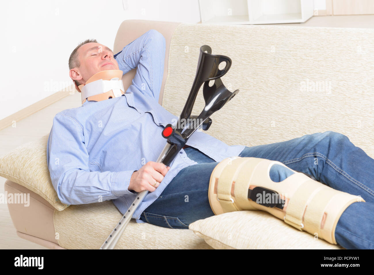 Man with leg in neck brace, knee cages and crutches for stabilization ...