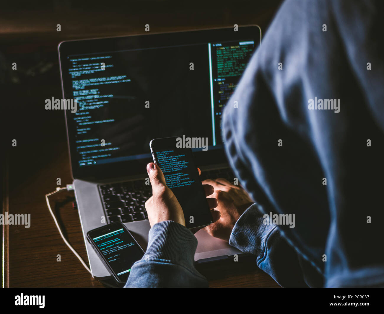 anonymous person in the hood sitting in front of computer working with ...