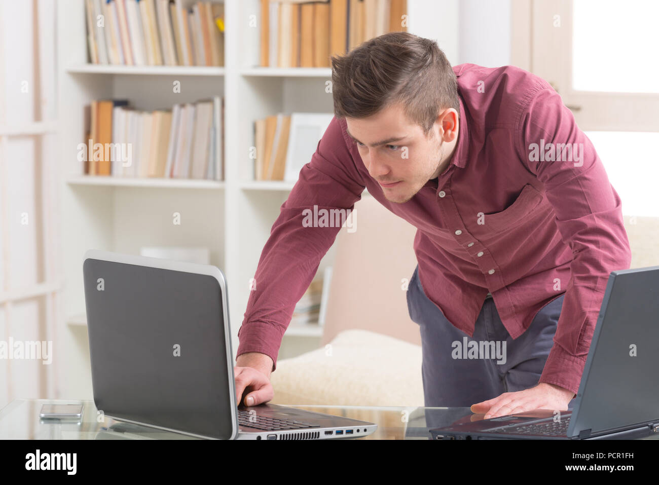 Young man working with two laptops at home Stock Photo - Alamy