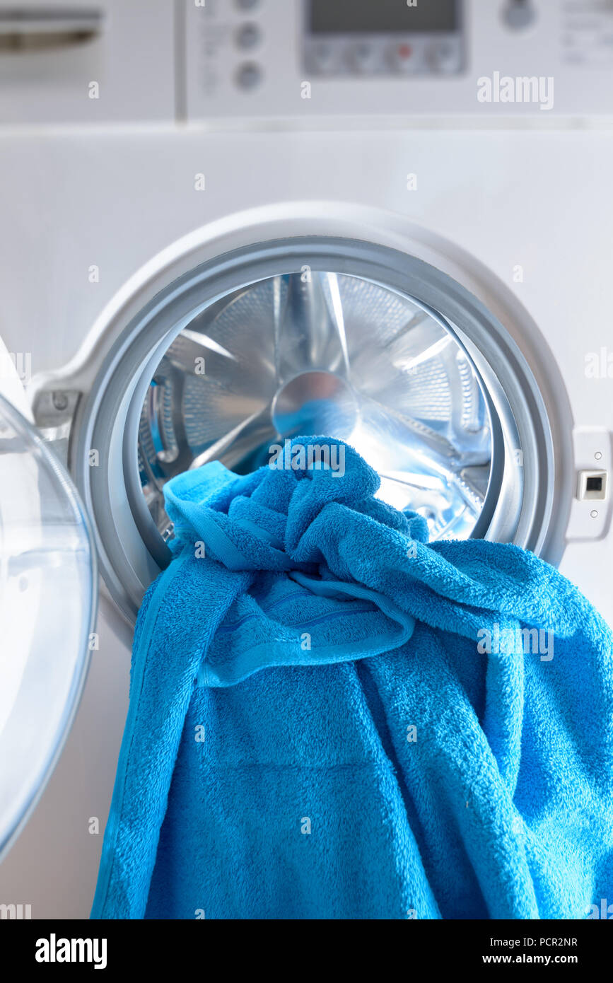 Modern washing machine loaded with blue towel Stock Photo - Alamy