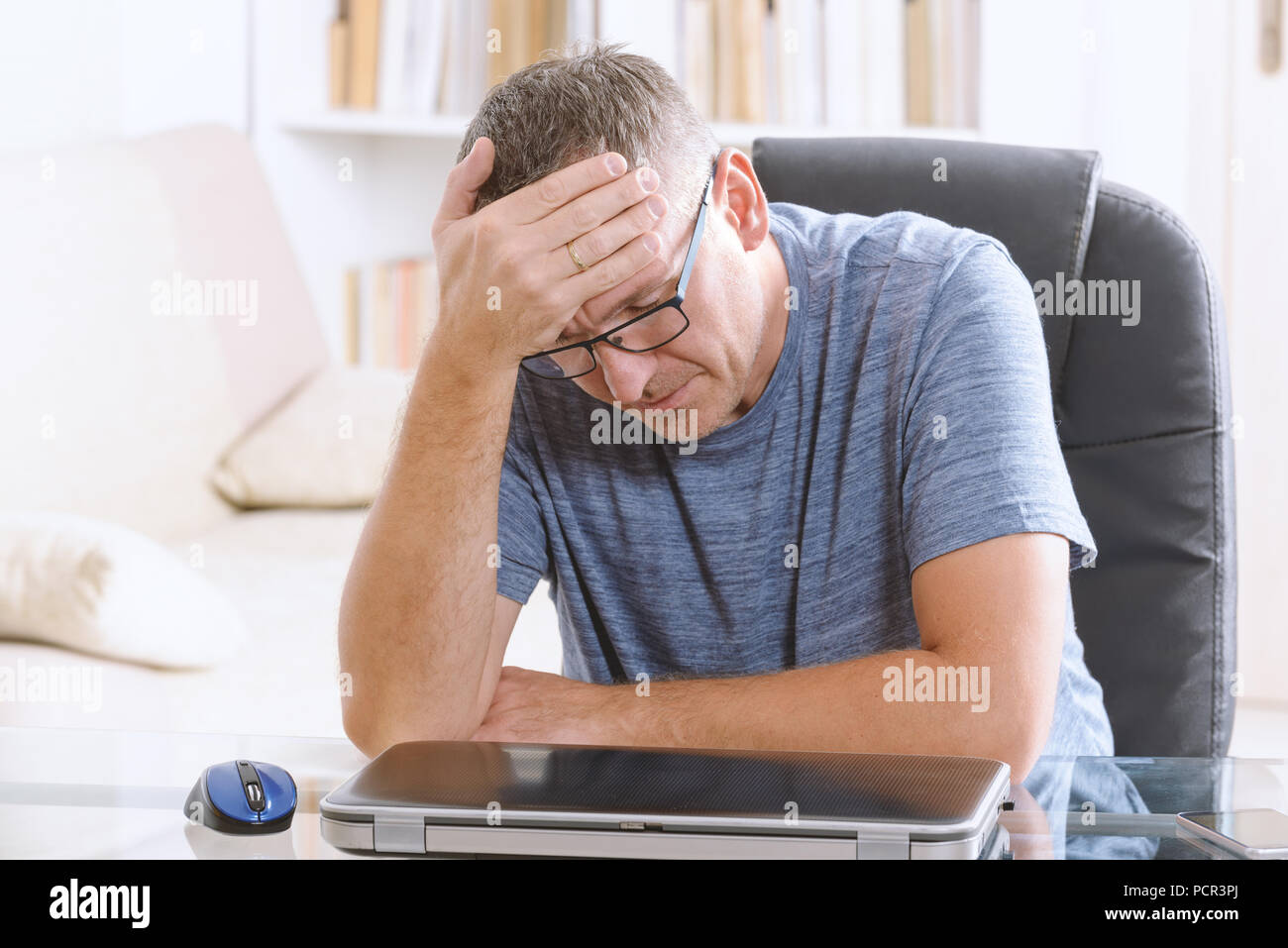 Tired man sitting at home office with notebook Stock Photo - Alamy