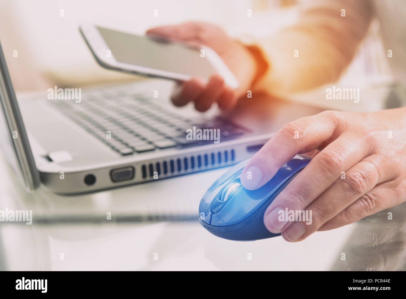 Hand on computer mouse and smartphone in the other. notebook in ...