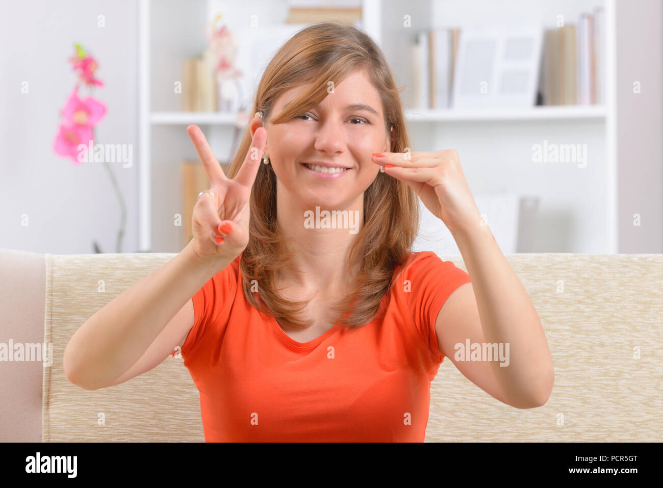 Beautiful smiling deaf woman using sign language showing V and E ...