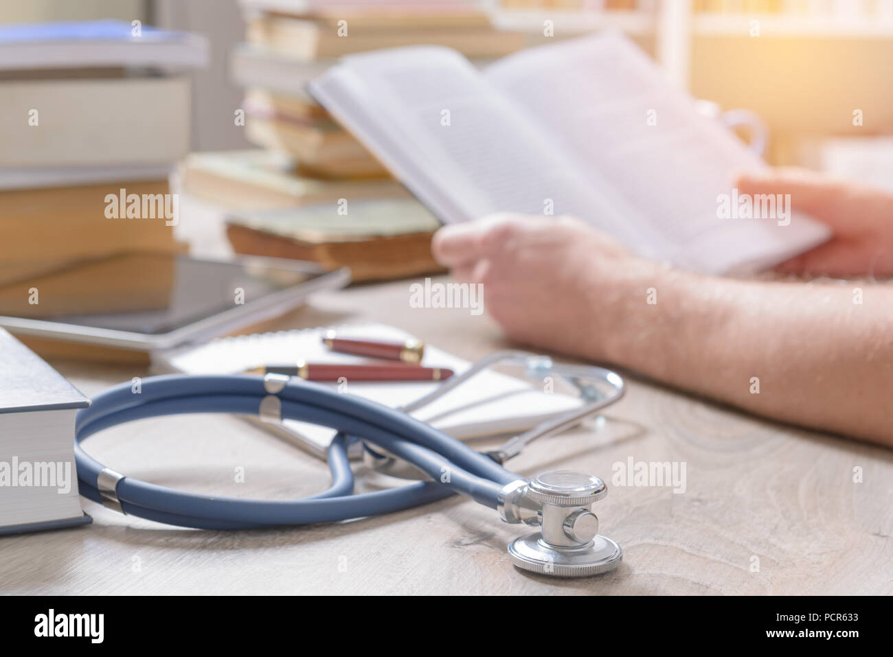 Young doctor is learning and preparing for the exam, he is using books ...
