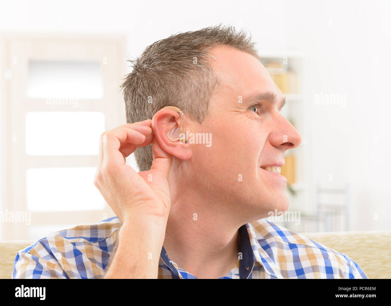 Man showing deaf aid in ear Stock Photo - Alamy