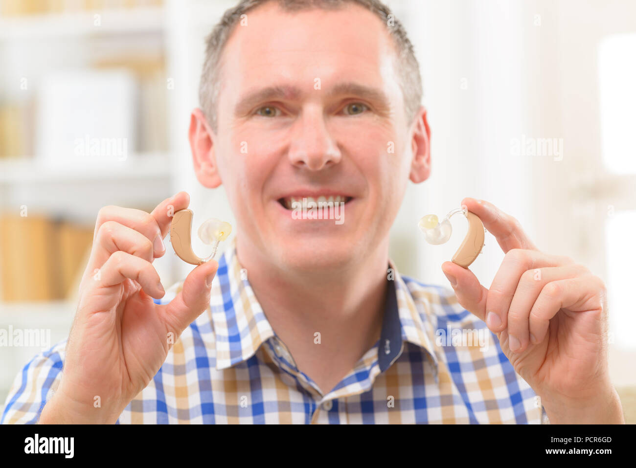 Man showing deaf aid in ear Stock Photo - Alamy