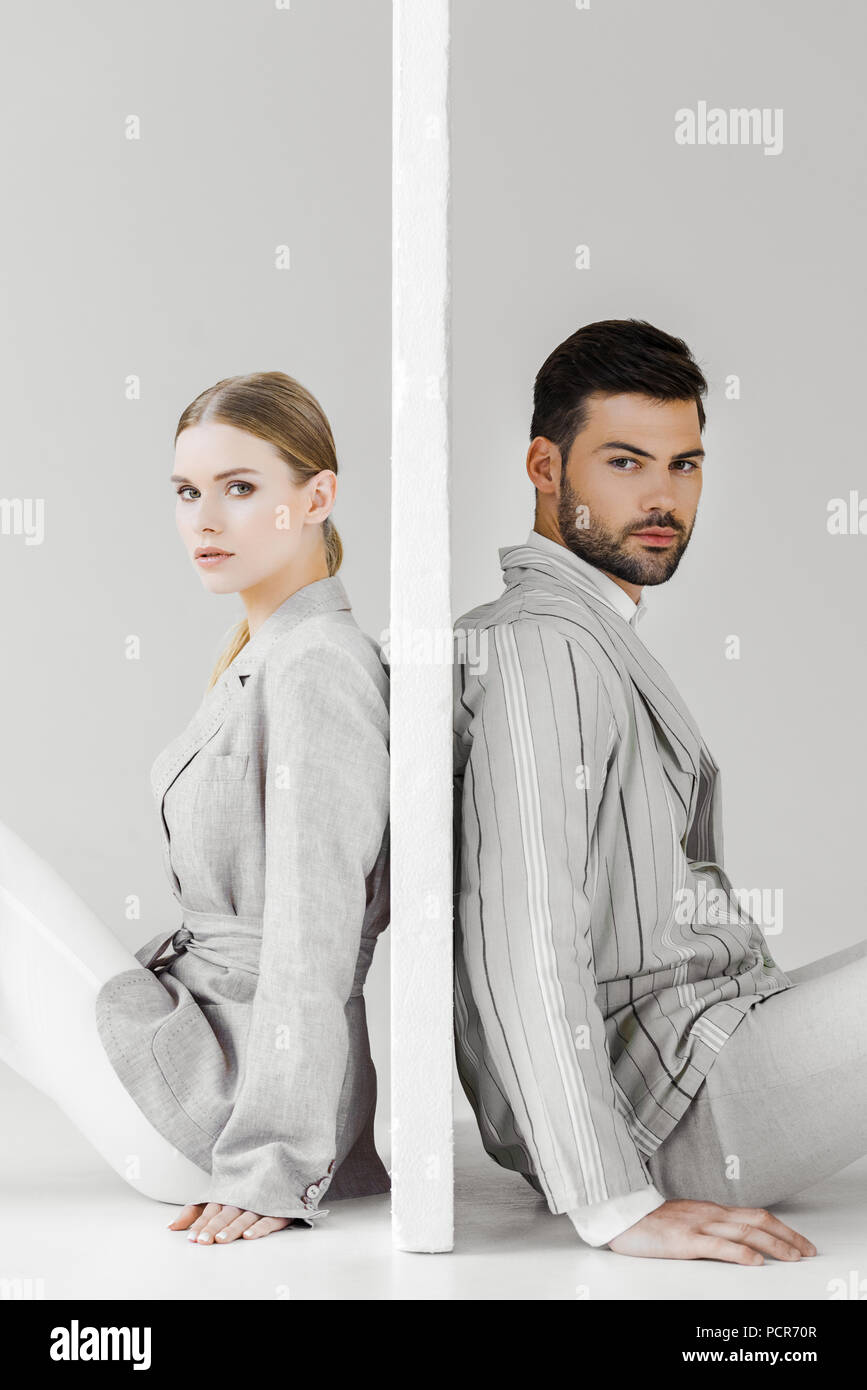 side view of couple of models in stylish jackets leaning back on sides ...