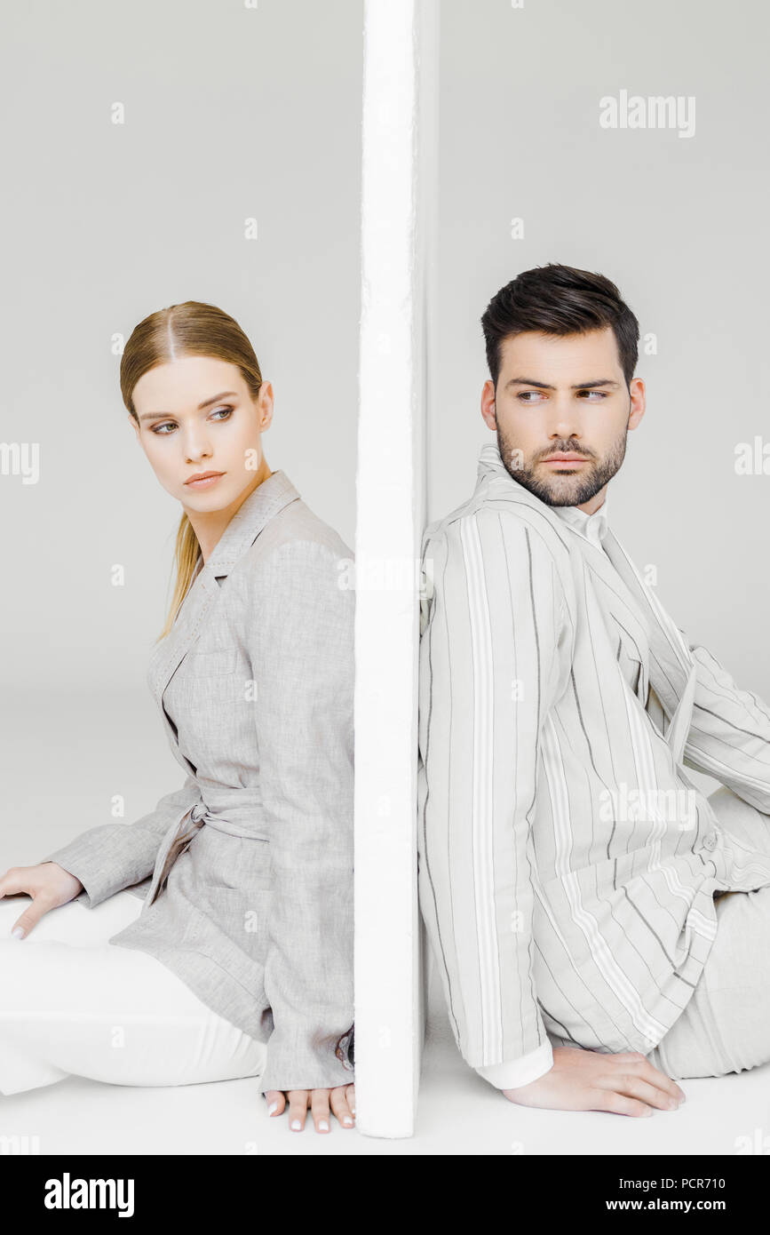 side view of couple of models in stylish jackets leaning back on sides ...