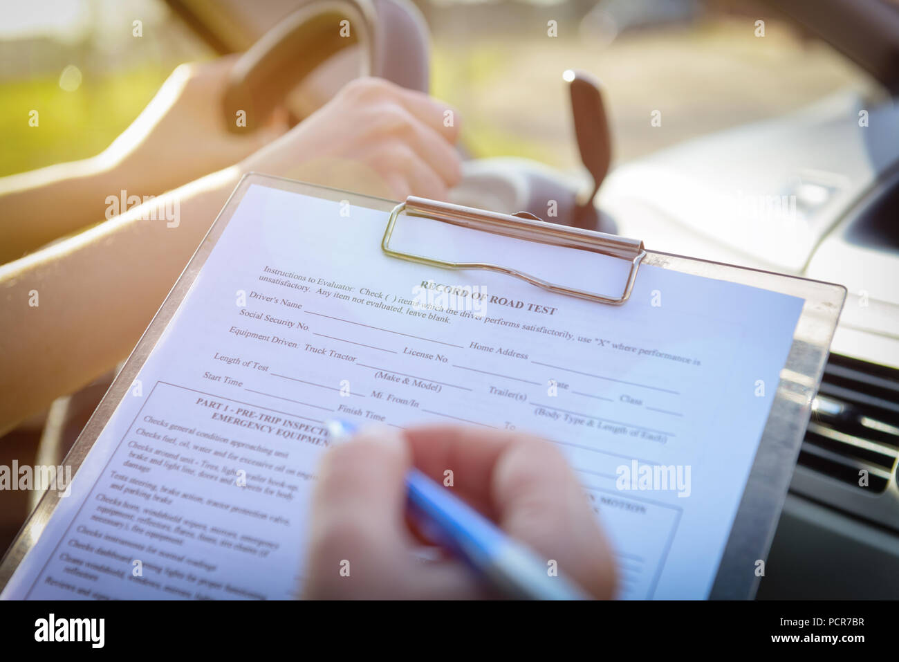 Examiner filling in driver's license road test form sitting with her ...