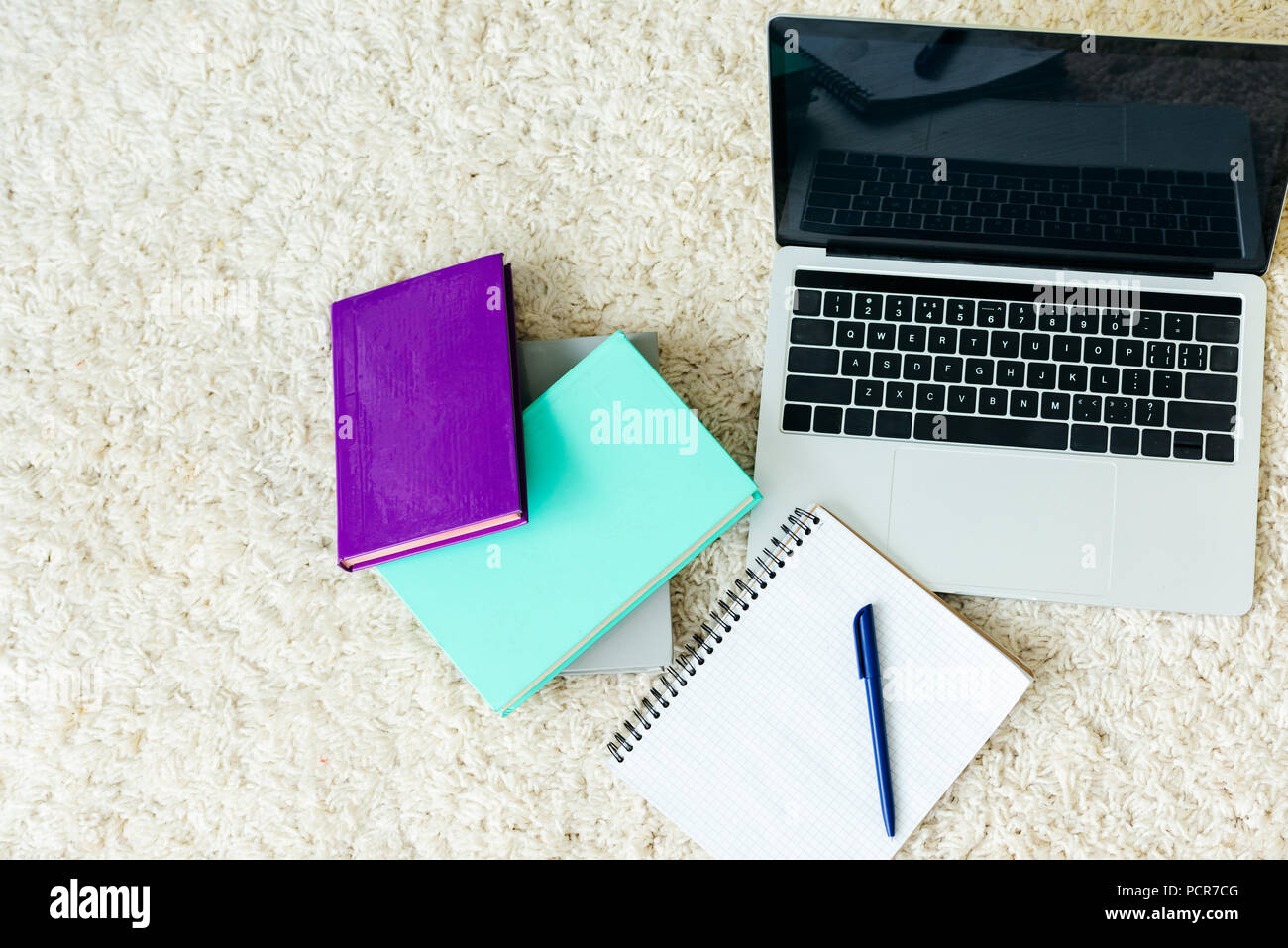 top view of books, notebook with pen and laptop with blank screen on ...