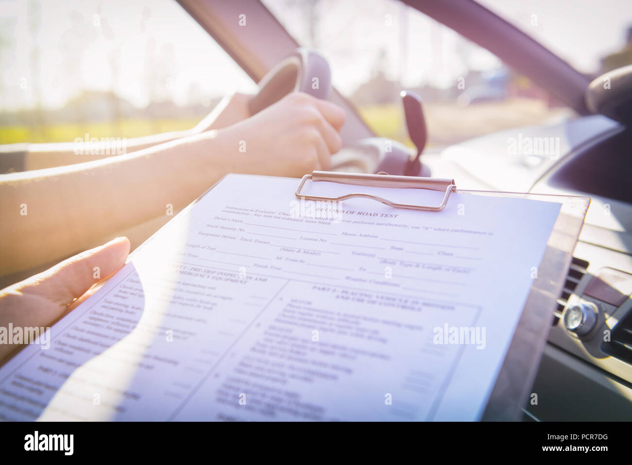 Examiner filling in driver's license road test form sitting with her ...