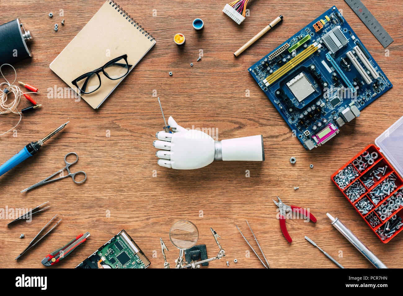 top view of prosthetic arm holding screwdriver on table with tools ...