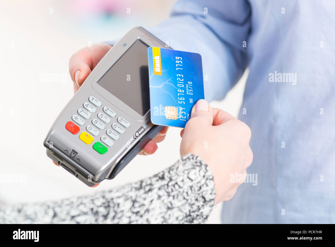 Hand holding contactless credit or debit card over wireless payment ...