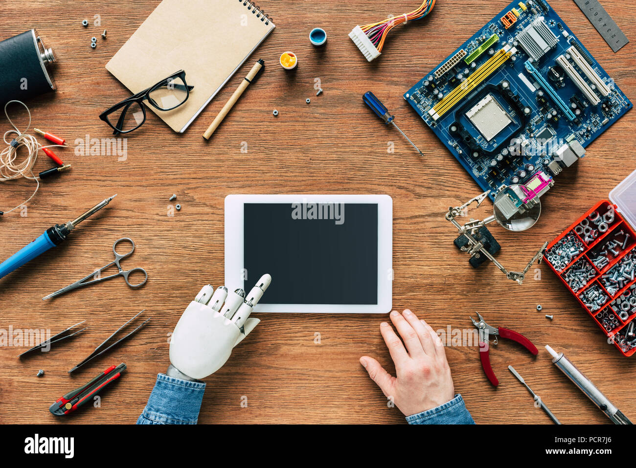 cropped image of man with robotic hand using digital tablet at table ...