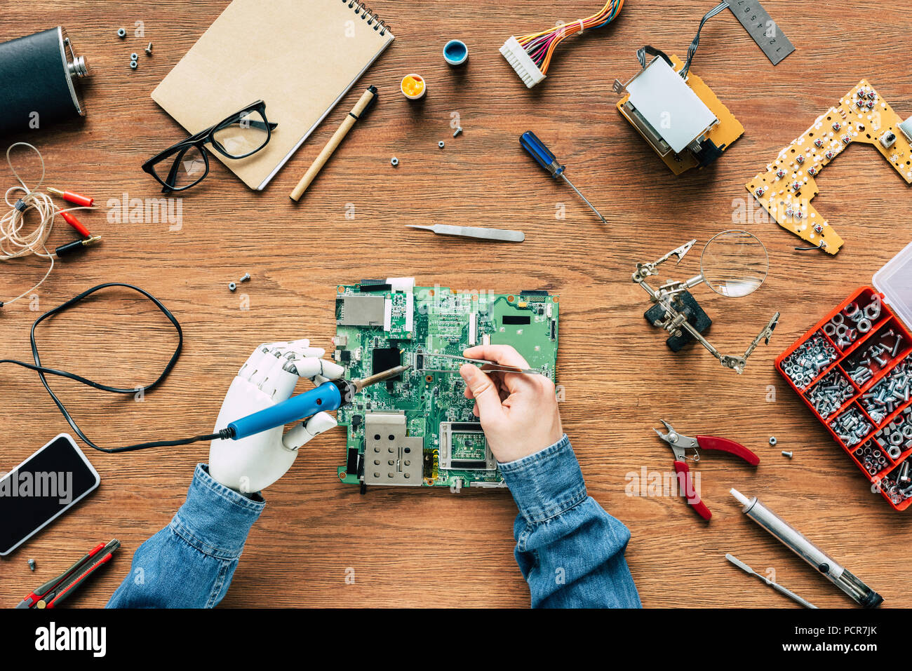 cropped image of electronic engineer with prosthetic arm fixing ...