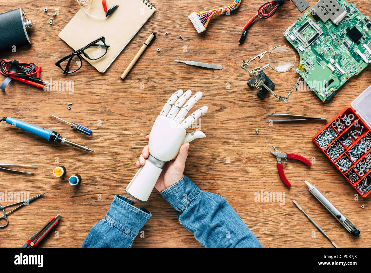 cropped image of man with amputee putting on robotic hand on table with ...