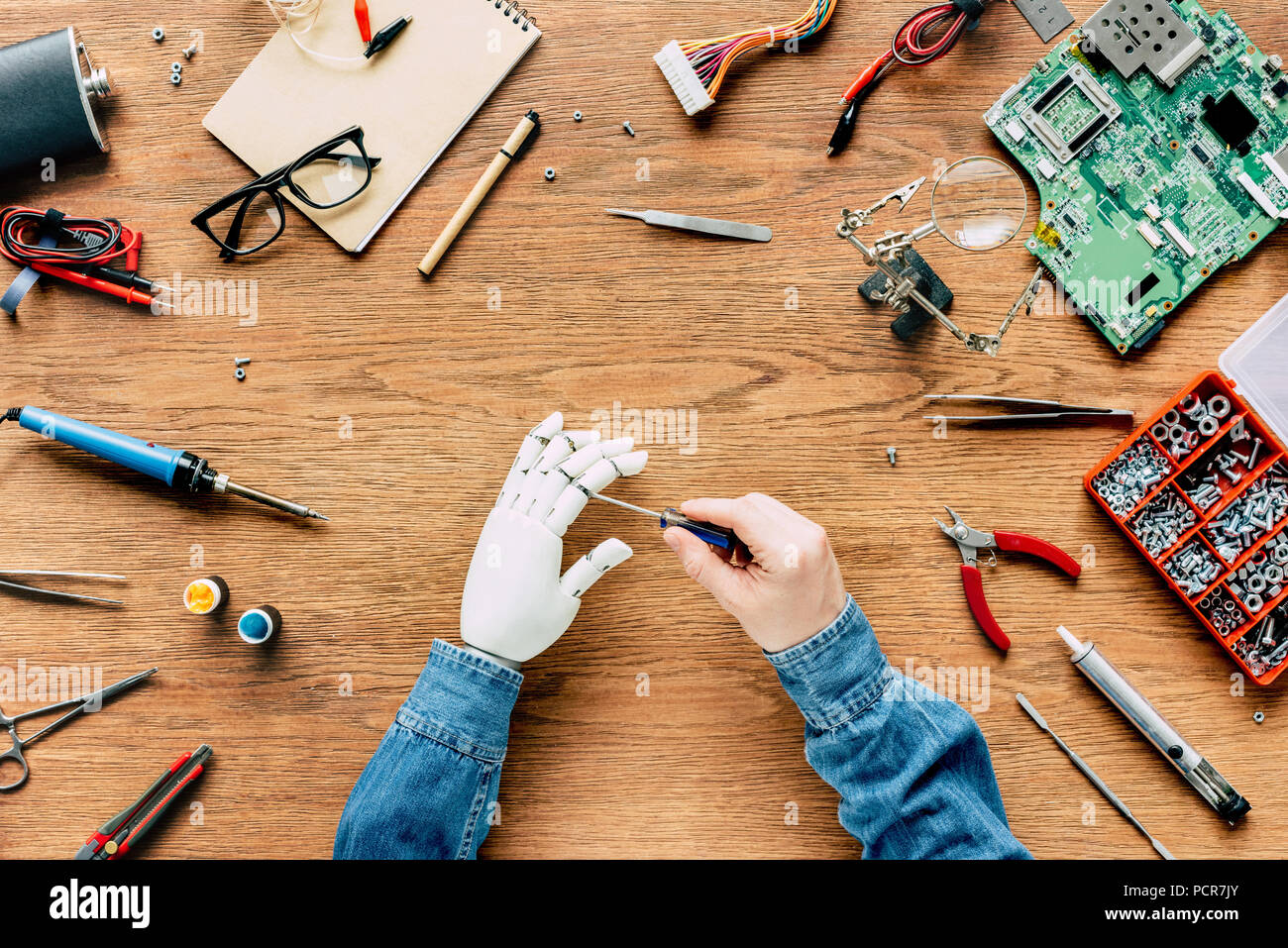 cropped image of man fixing prosthetic arm by screwdriver at wooden ...