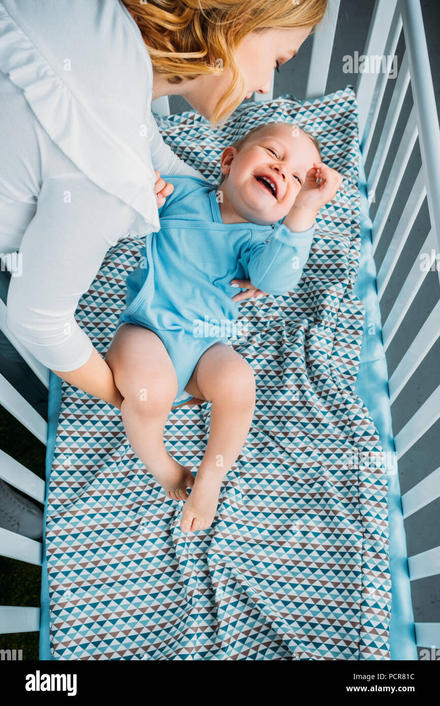 high angle view of mother putting her little child into crib Stock ...