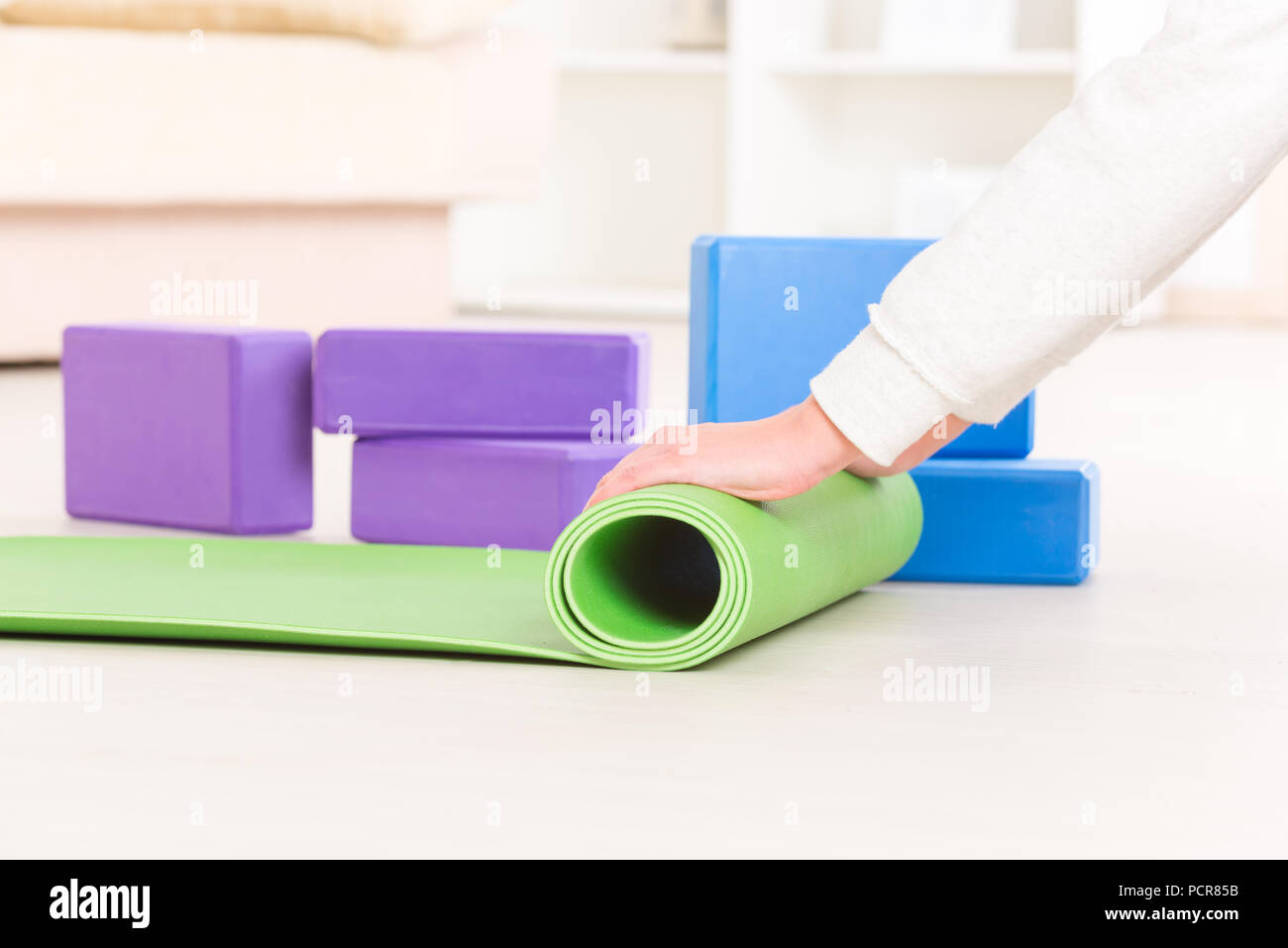 Rolling up a yoga mat on the floor Stock Photo - Alamy