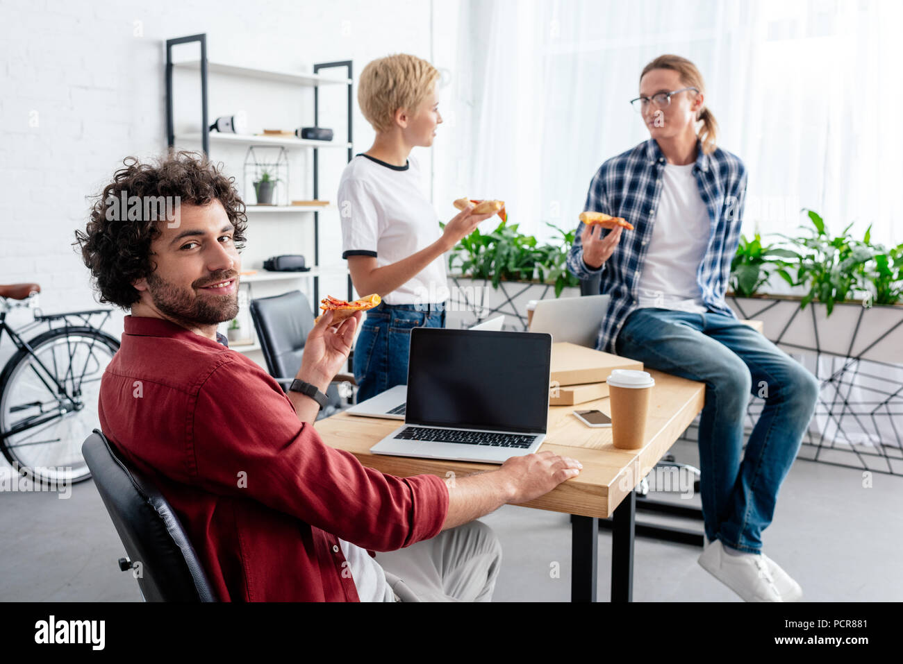young start up team eating pizza together while working in office Stock ...