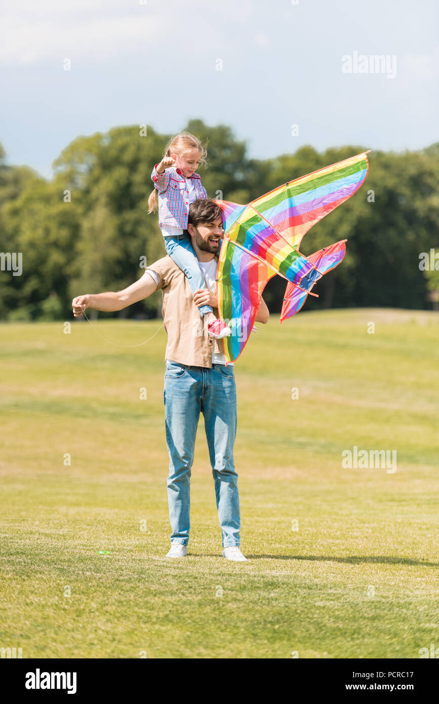 happy father carrying little daughter on neck and playing with colorful ...