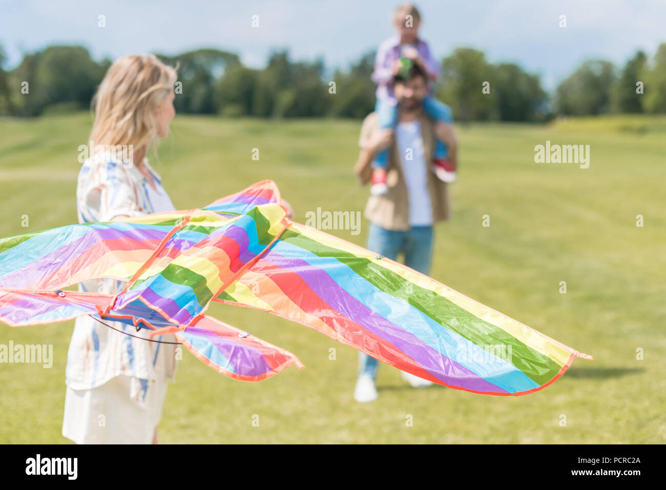 young woman holding kite while father carrying little daughter on neck ...