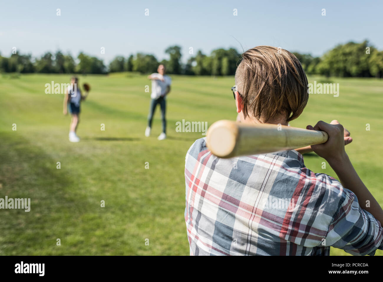 back view of teenage boy playing baseball with friends in park Stock ...