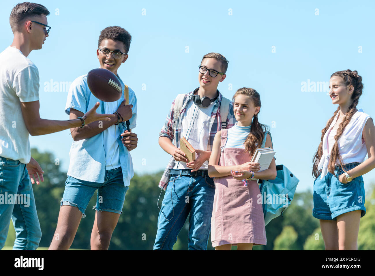 happy multiethnic teenagers playing with rugby ball in park Stock Photo ...