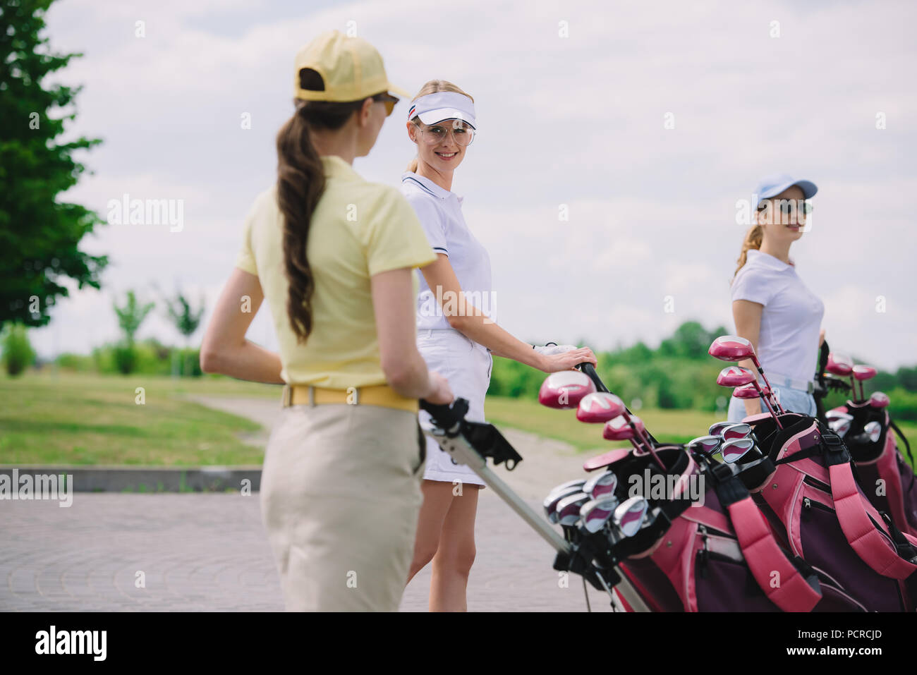 selective focus of female golfers with golf equipment walking at golf ...