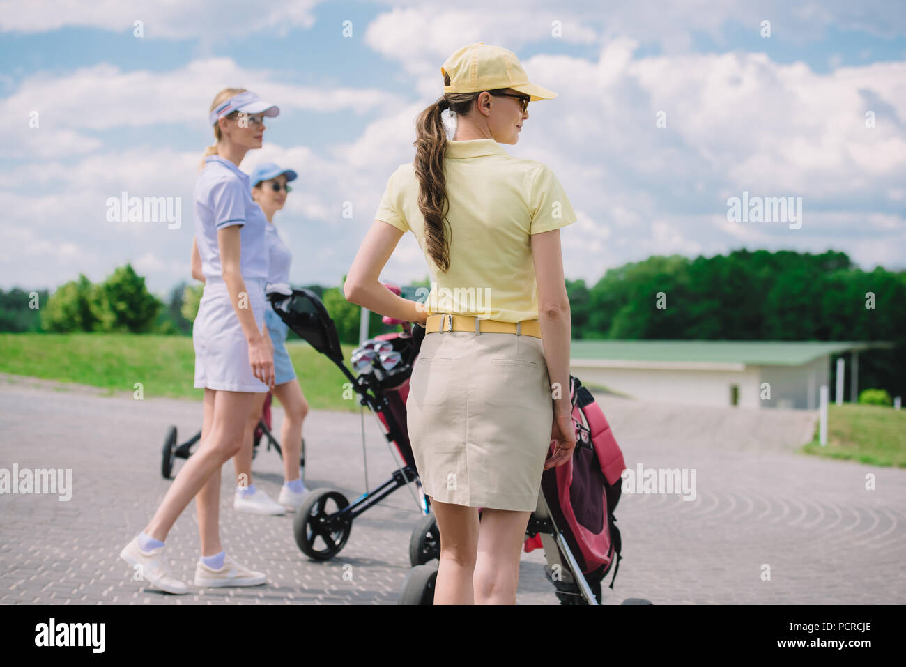 selective focus of female golfers with golf equipment walking at golf ...