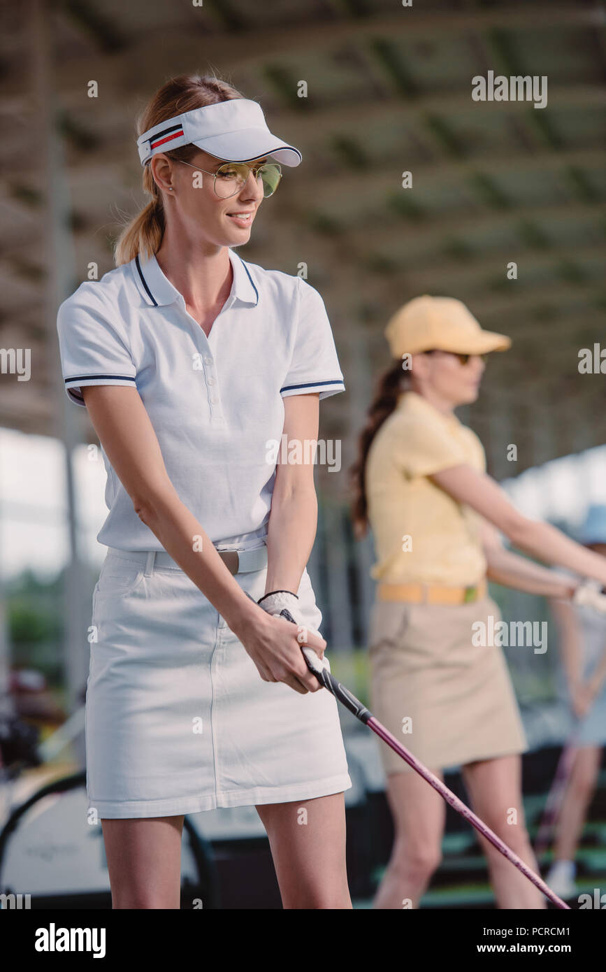 selective focus of smiling woman playing golf with friend at golf ...