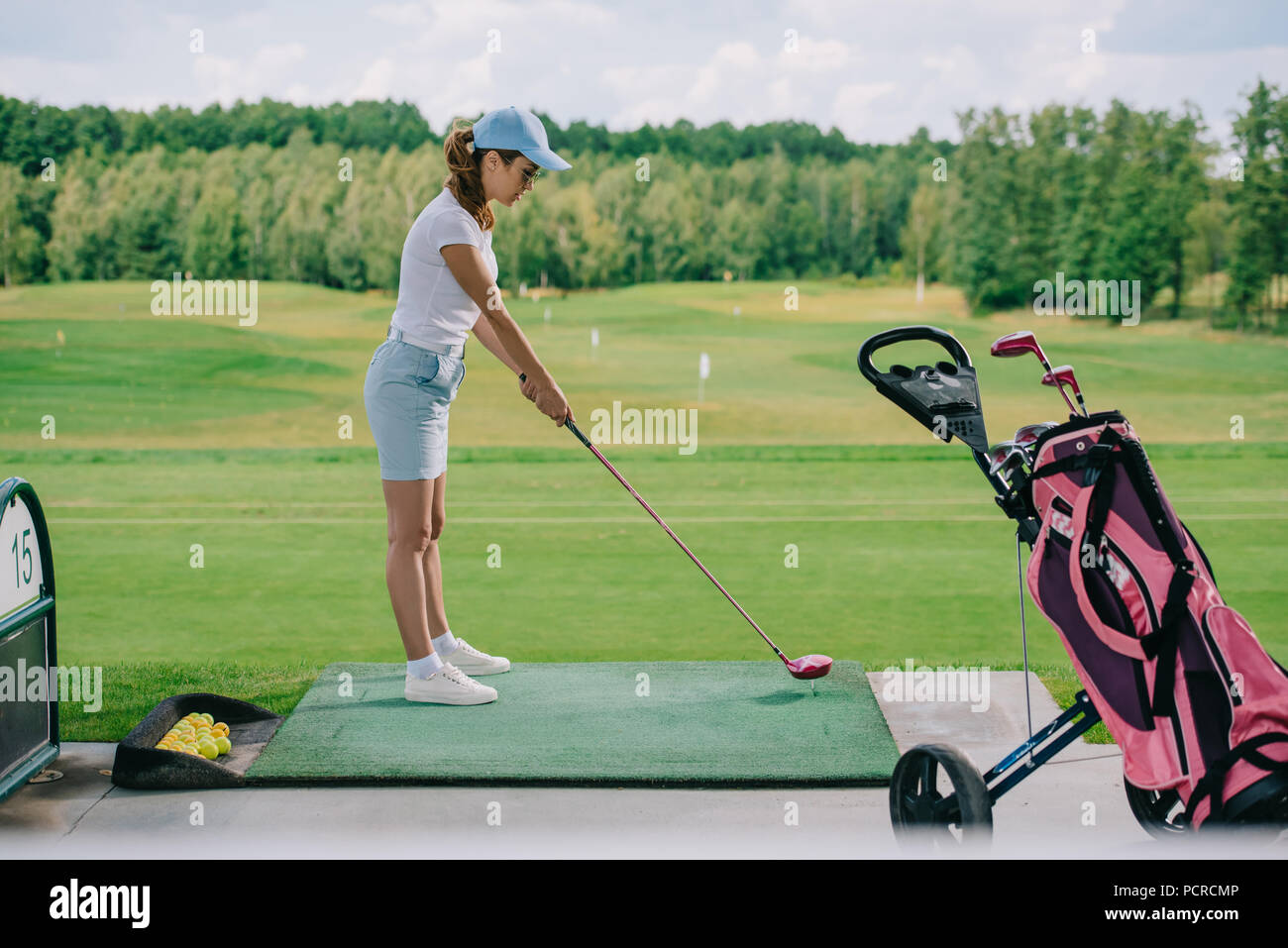 side view of woman in polo and cap playing golf at golf course Stock ...