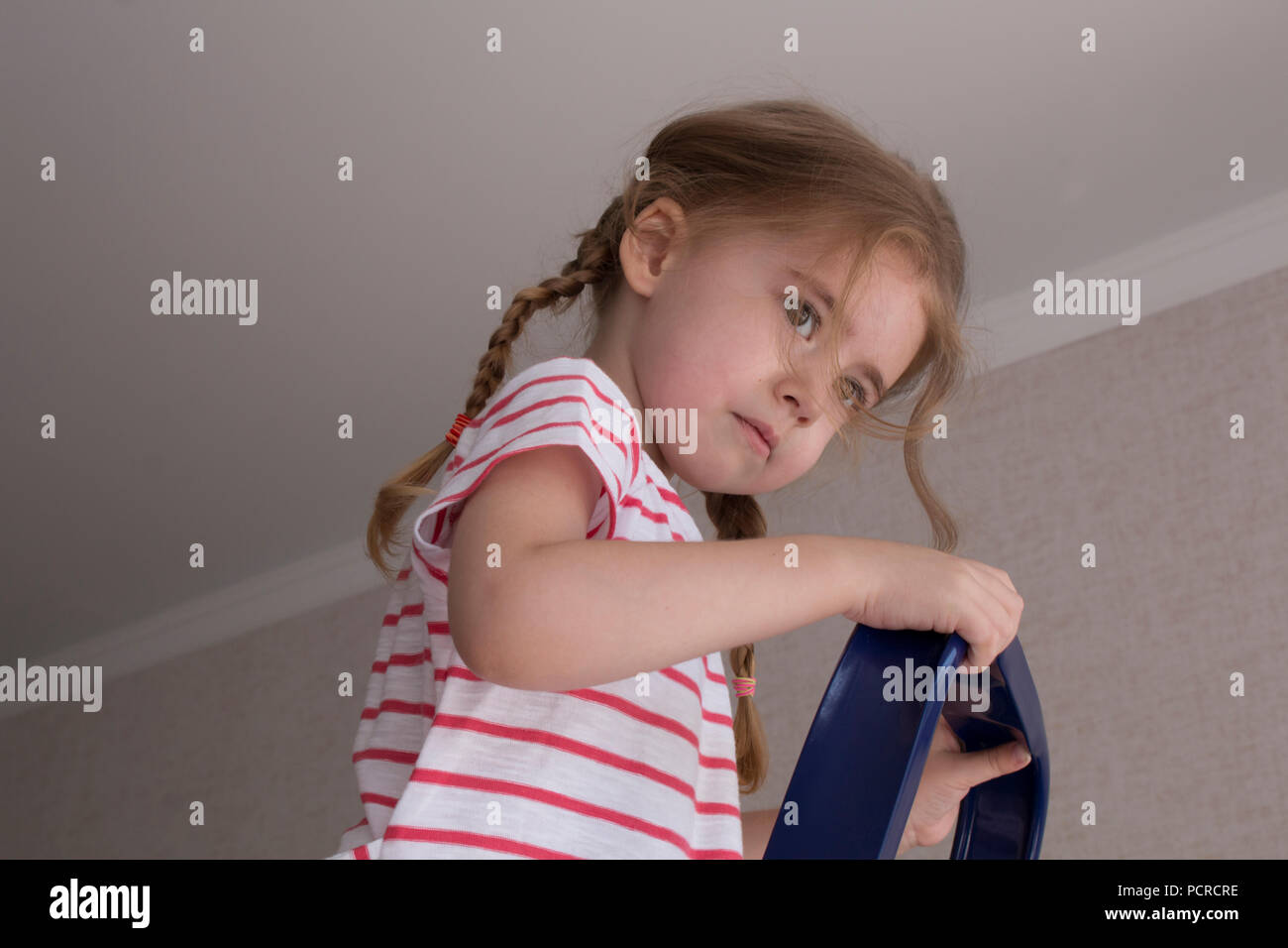 Close-up portrait of little girl is standing on the top of a ladder ...