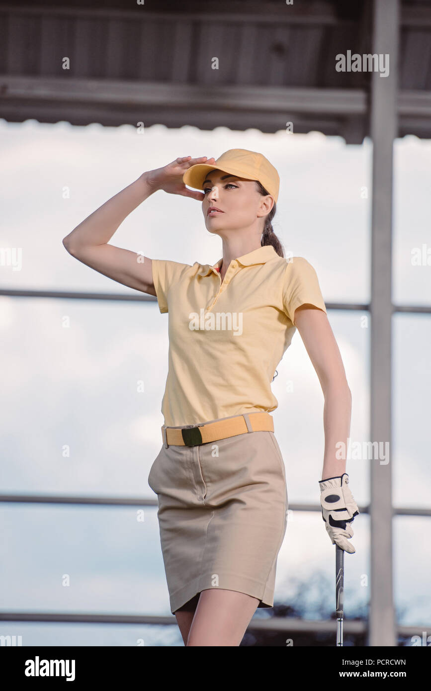 portrait of pensive female golf player in cap with golf club looking ...
