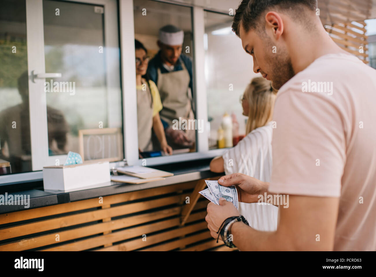 young man counting money while standing in line at food truck Stock ...