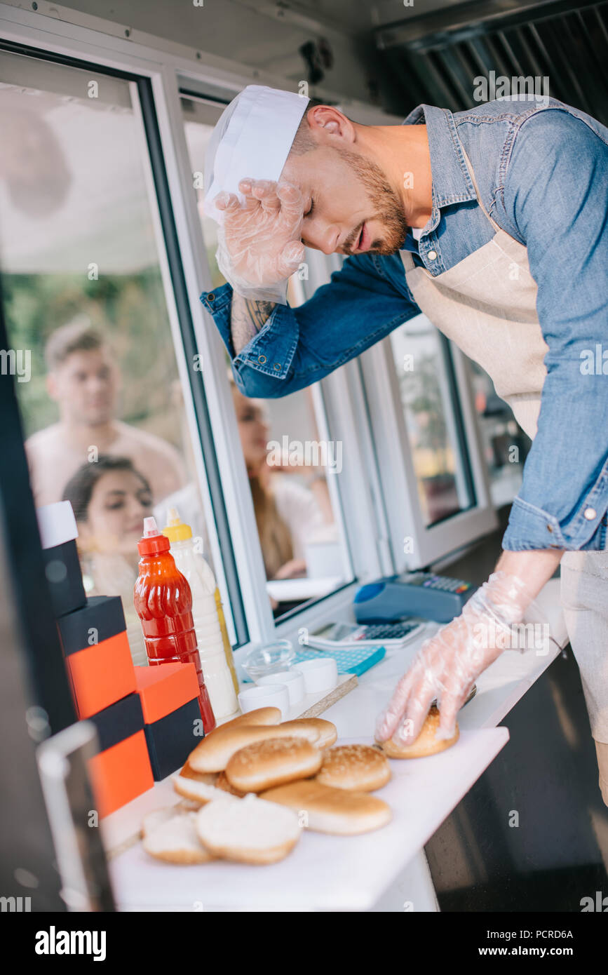 tired chef working in food truck while customers waiting outside Stock ...