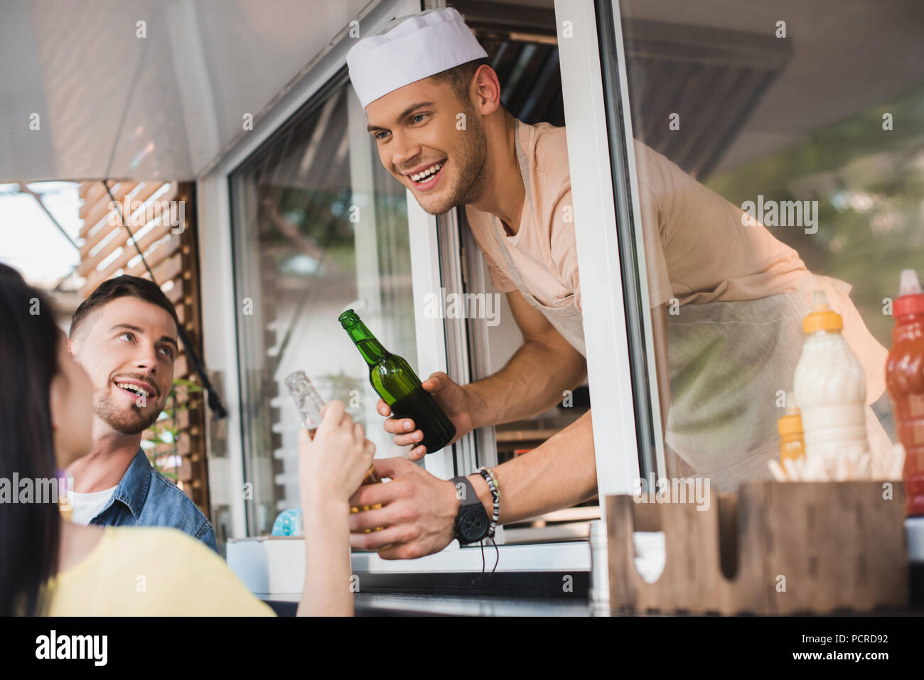 smiling chef giving drinks to customers from food truck Stock Photo - Alamy