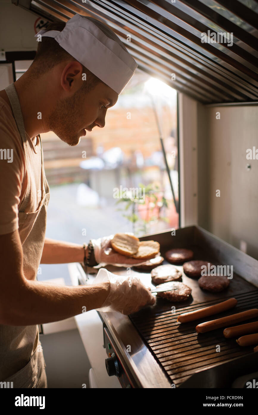 side view of chef preparing burgers in food truck Stock Photo - Alamy