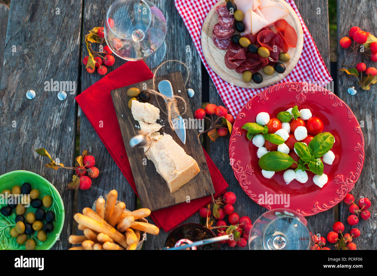 Italian picnic with red wine, Parmesan, ham, caprese salad and olives ...