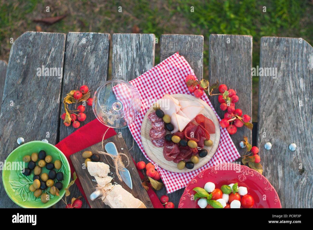 Italian picnic with red wine, Parmesan, ham, caprese salad and olives ...