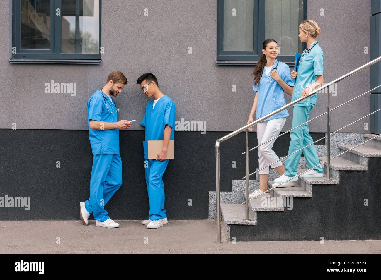 multicultural male medical students looking at smartphone near medical ...