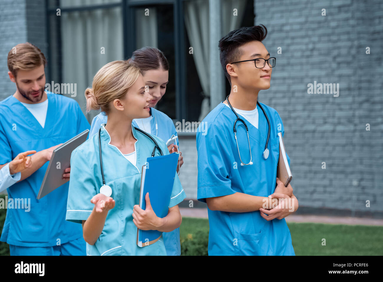 multicultural students talking while walking on street near medical ...