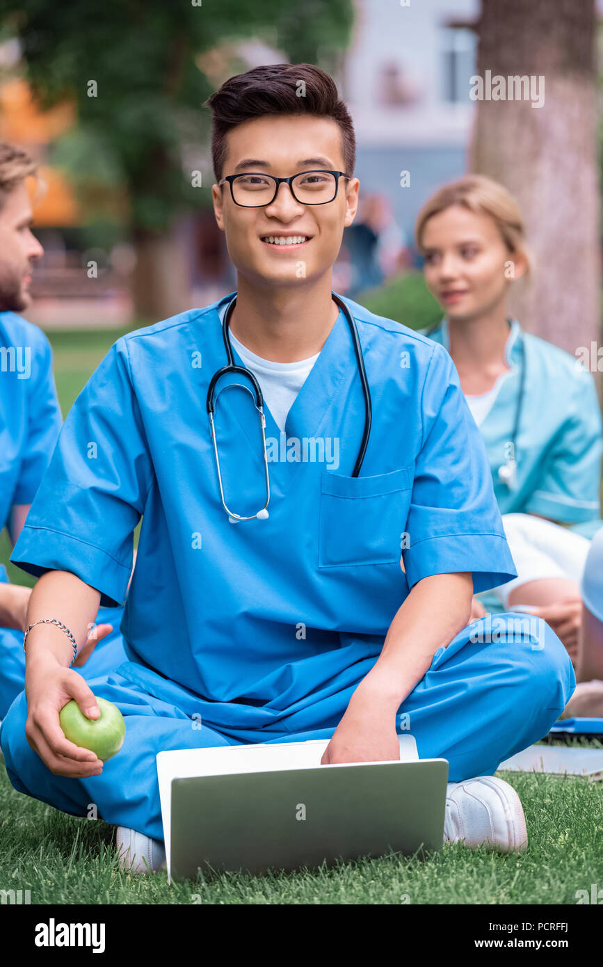 handsome asian medical student holding apple with laptop and looking at ...