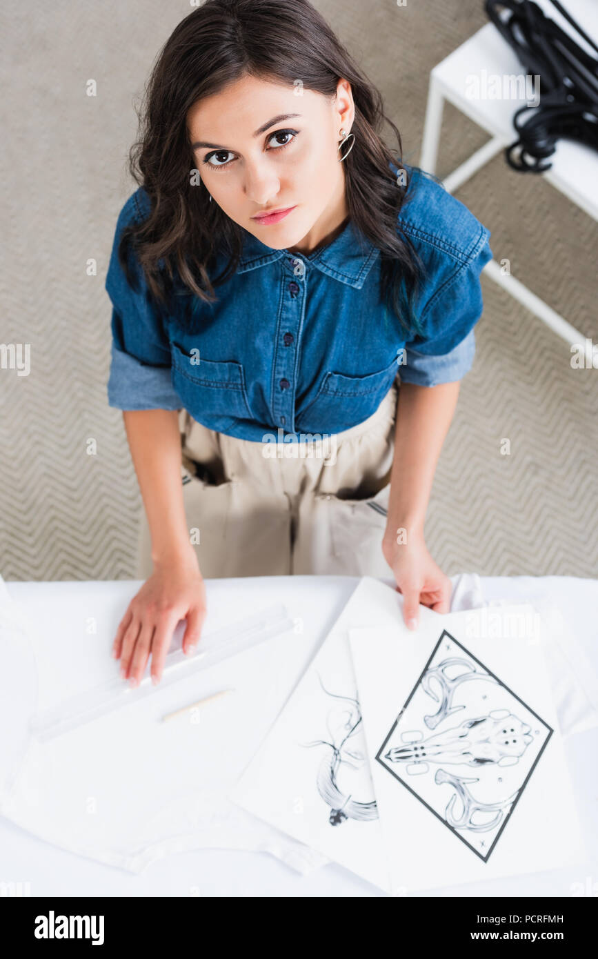 overhead view of female fashion designer looking at camera and ...