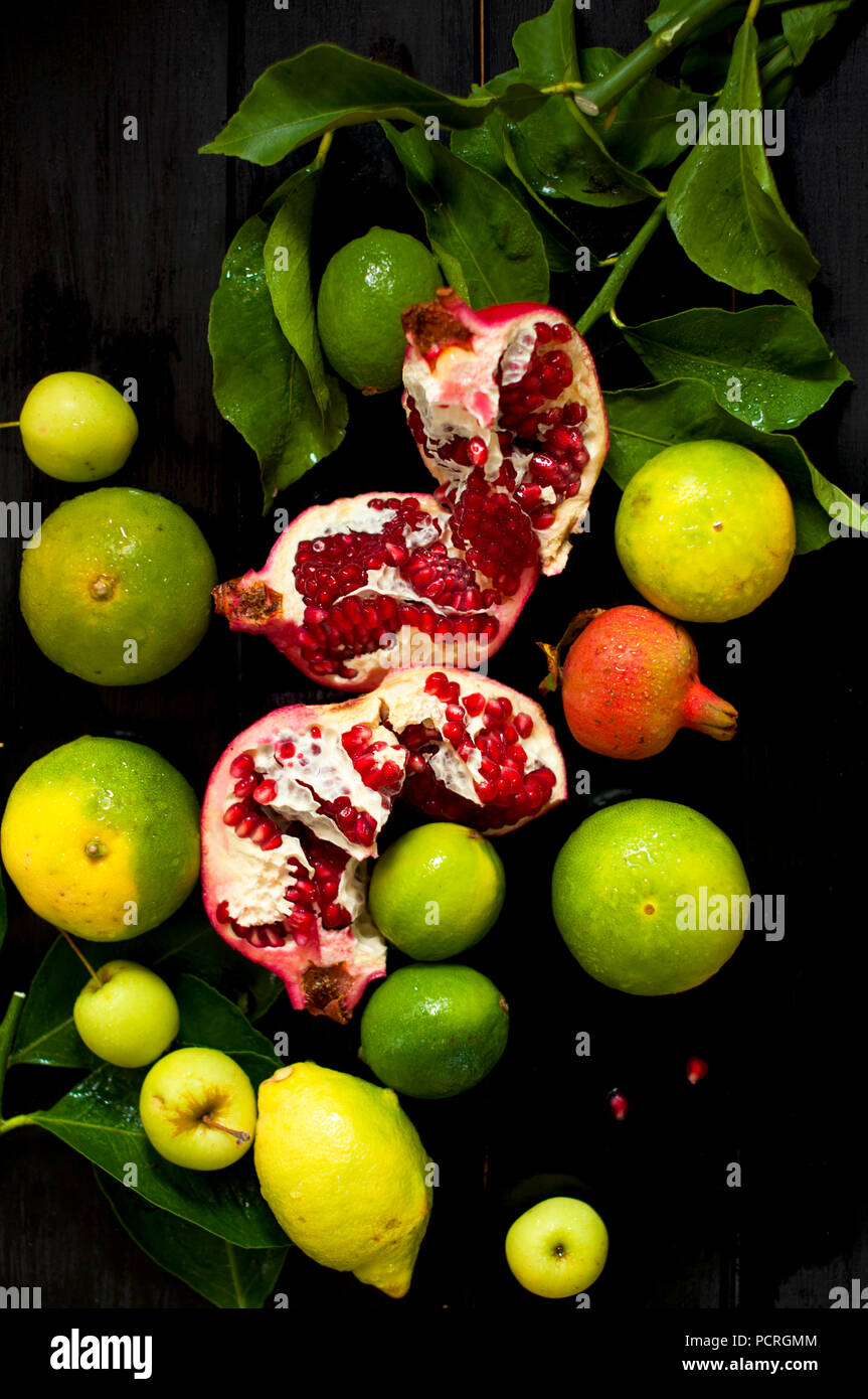 lemon on a branch and limes. chopped grenade. on a black background ...