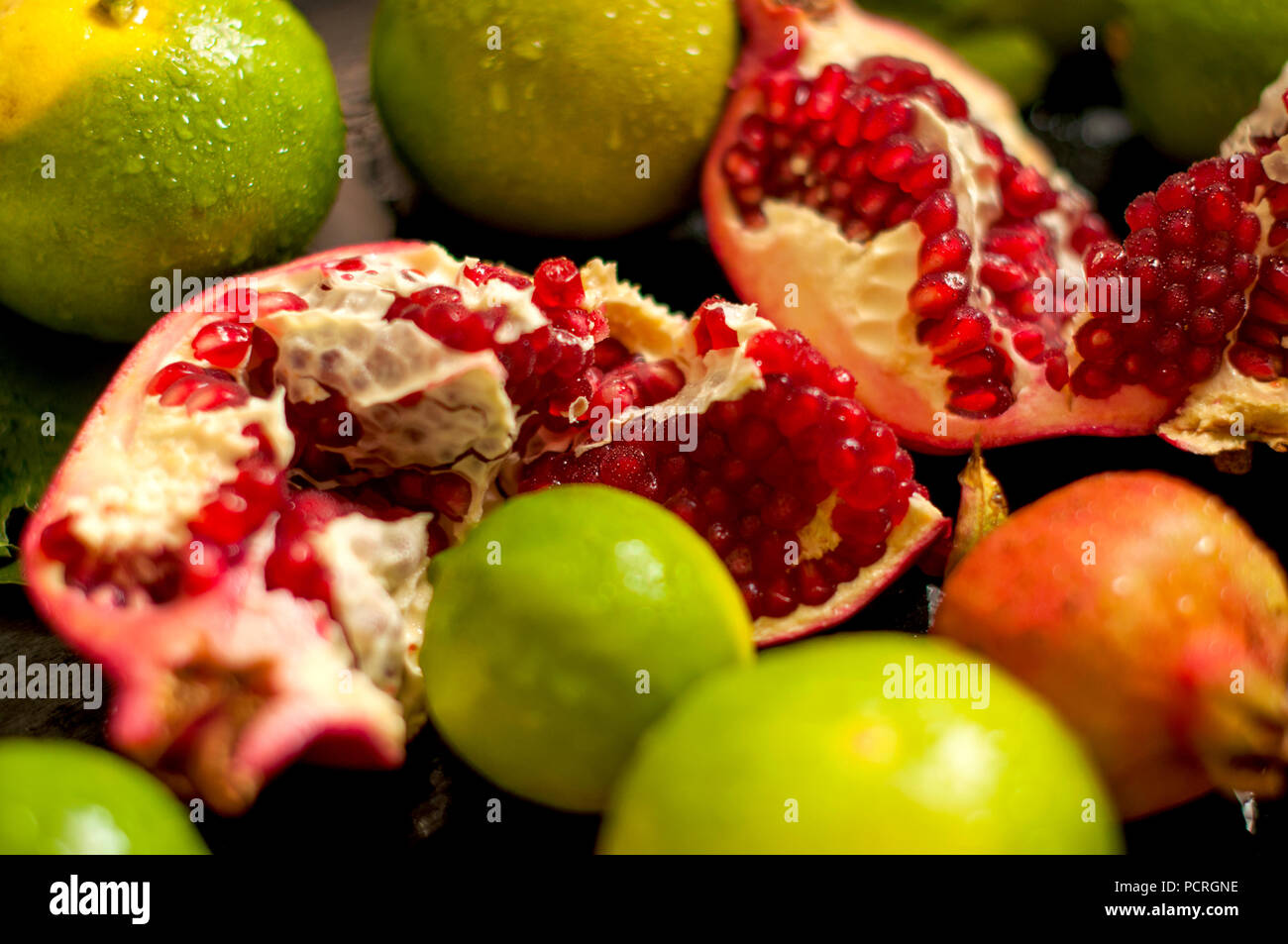 lemon on a branch and limes. chopped grenade. on a black background ...
