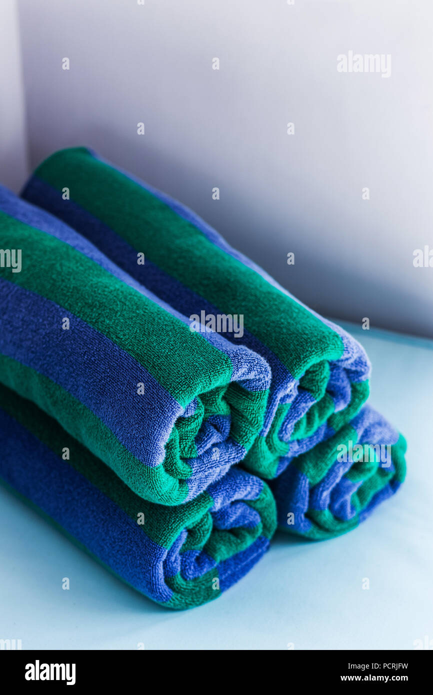 Rolled multicolor pool towels near white wall Stock Photo - Alamy